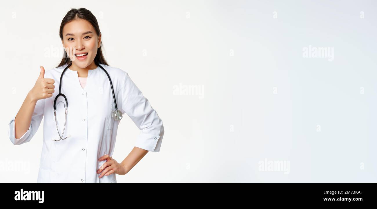 Health and hospital concept. Smiling asian doctor shows thumbs up in ...