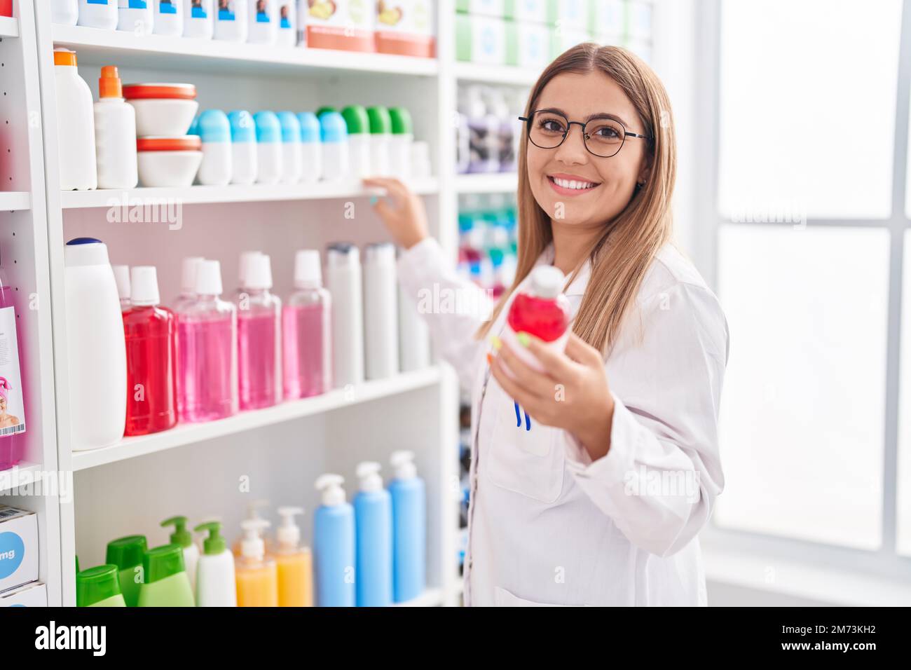 Young beautiful hispanic woman pharmacist smiling confident holding ...