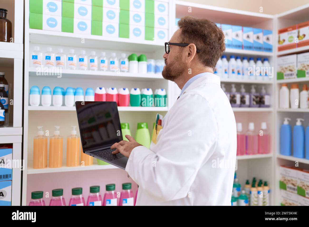 Middle age man pharmacist using laptop working at pharmacy Stock Photo ...