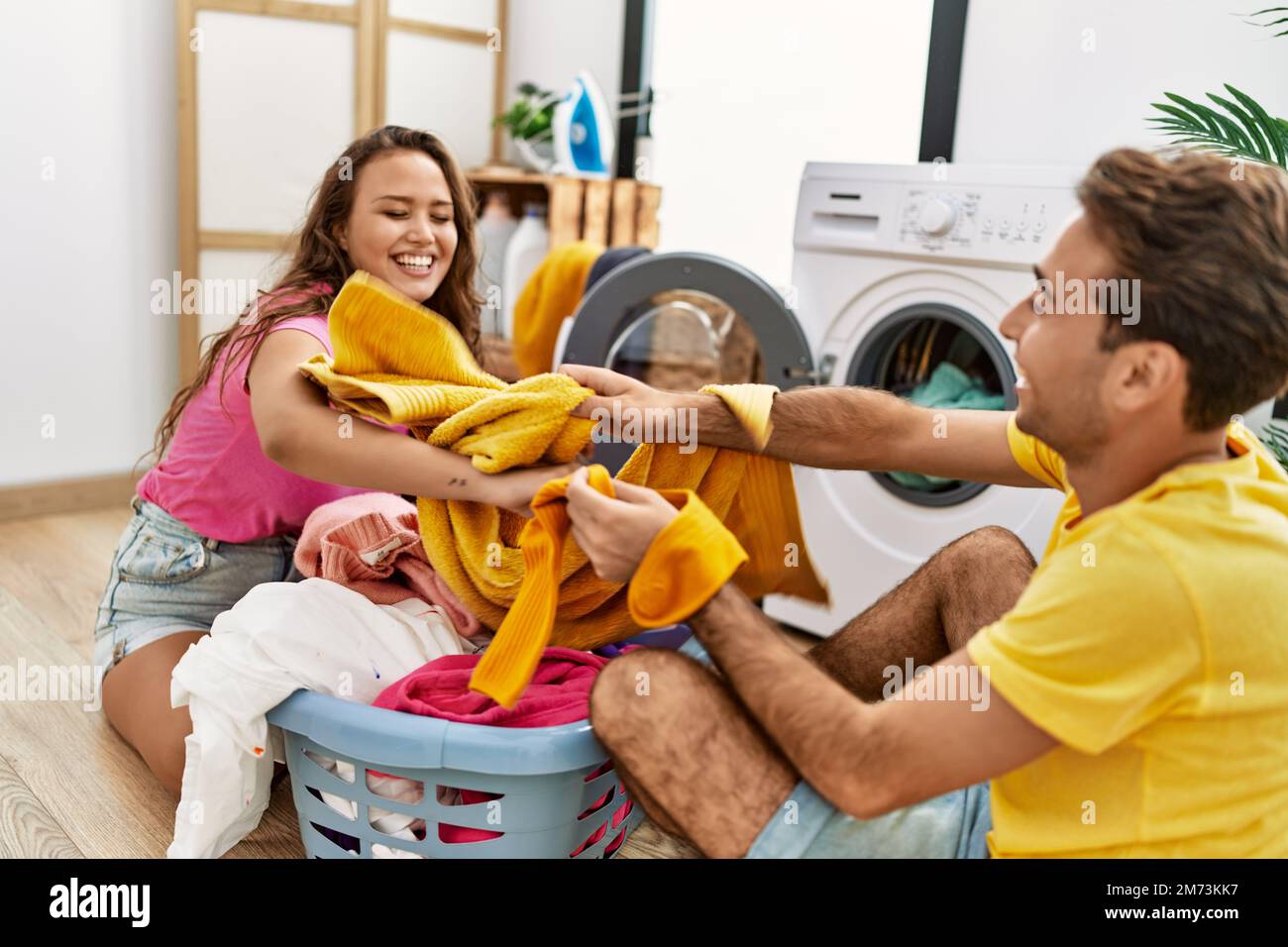 Man and woman couple cleaning clothes using washing machine at laundry ...