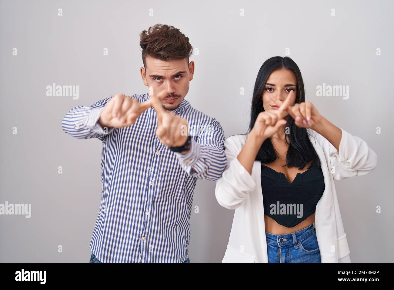 Young hispanic couple standing over white background rejection ...