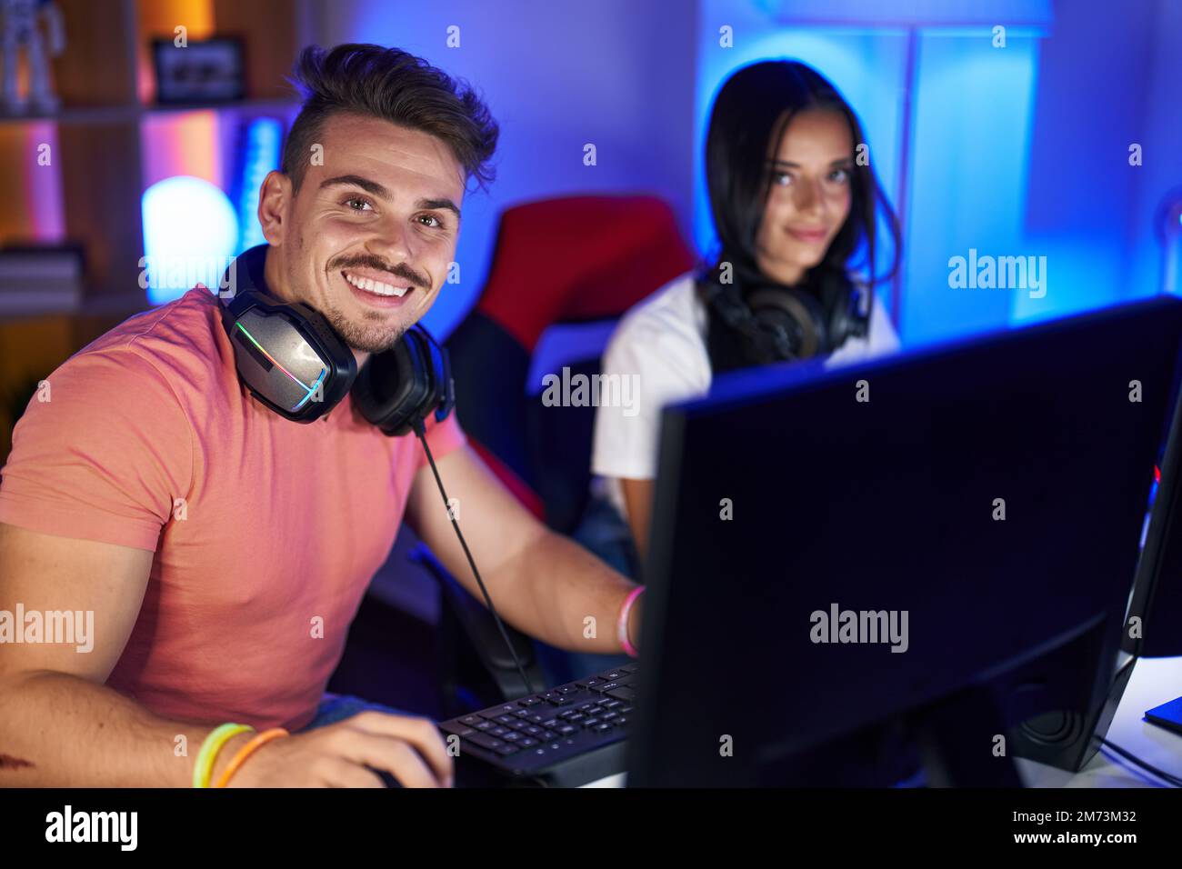 Man and woman streamers playing video game using computer at gaming ...