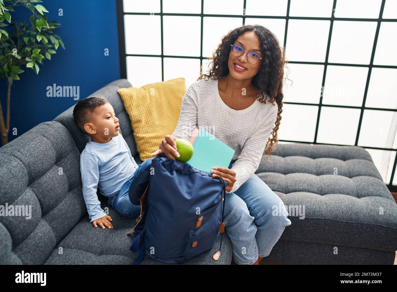 Mother and son prepare school backpack sitting on sofa at home Stock ...