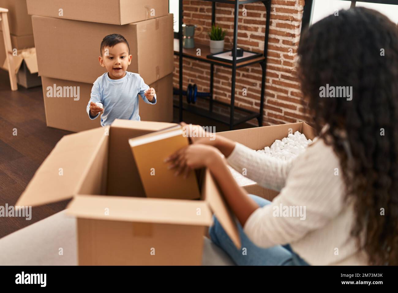 Mother and son unpacking cardboard box sitting on sofa at new home ...