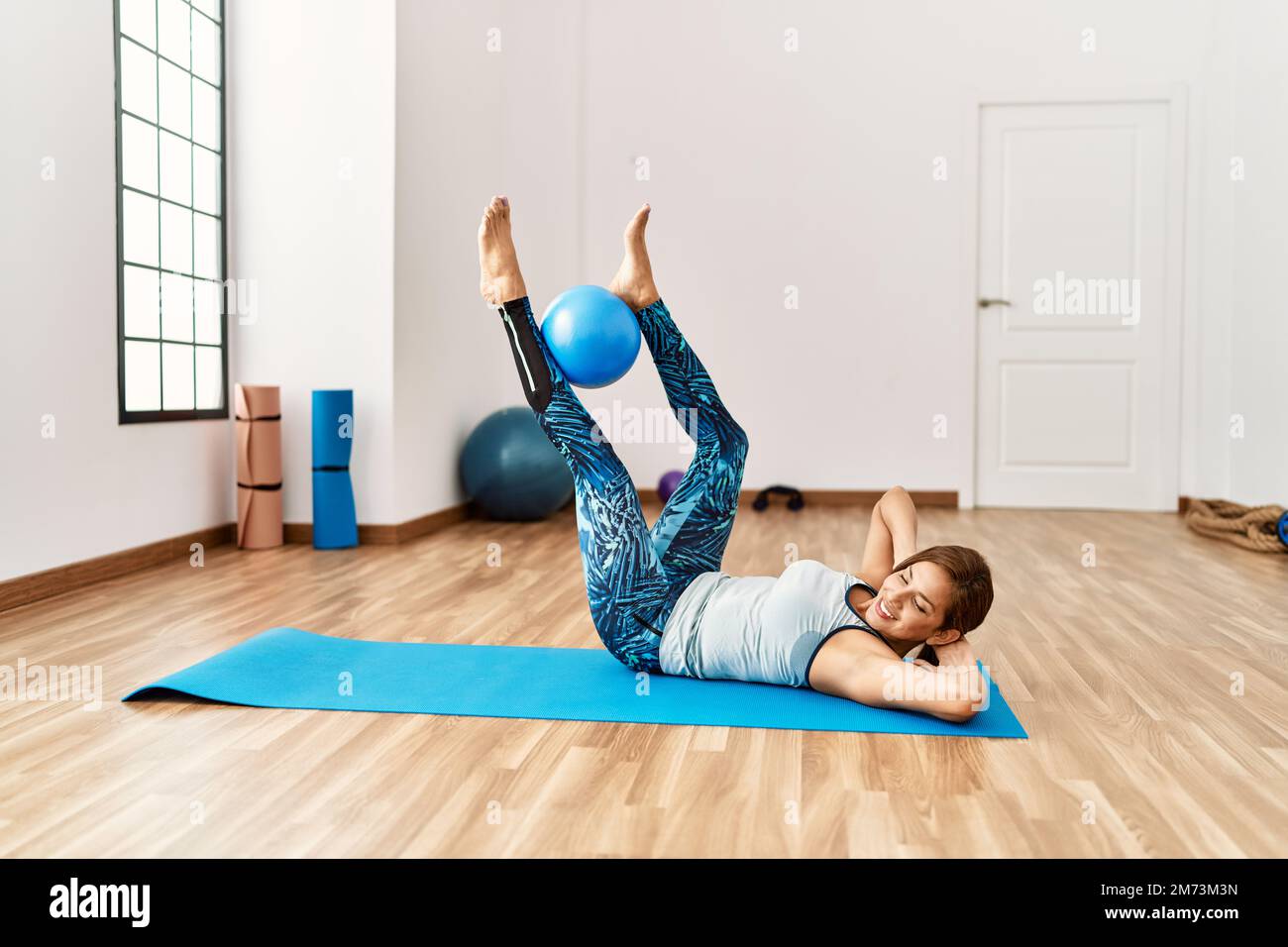 Young latin woman smiling confident training abs exercise using ball at ...