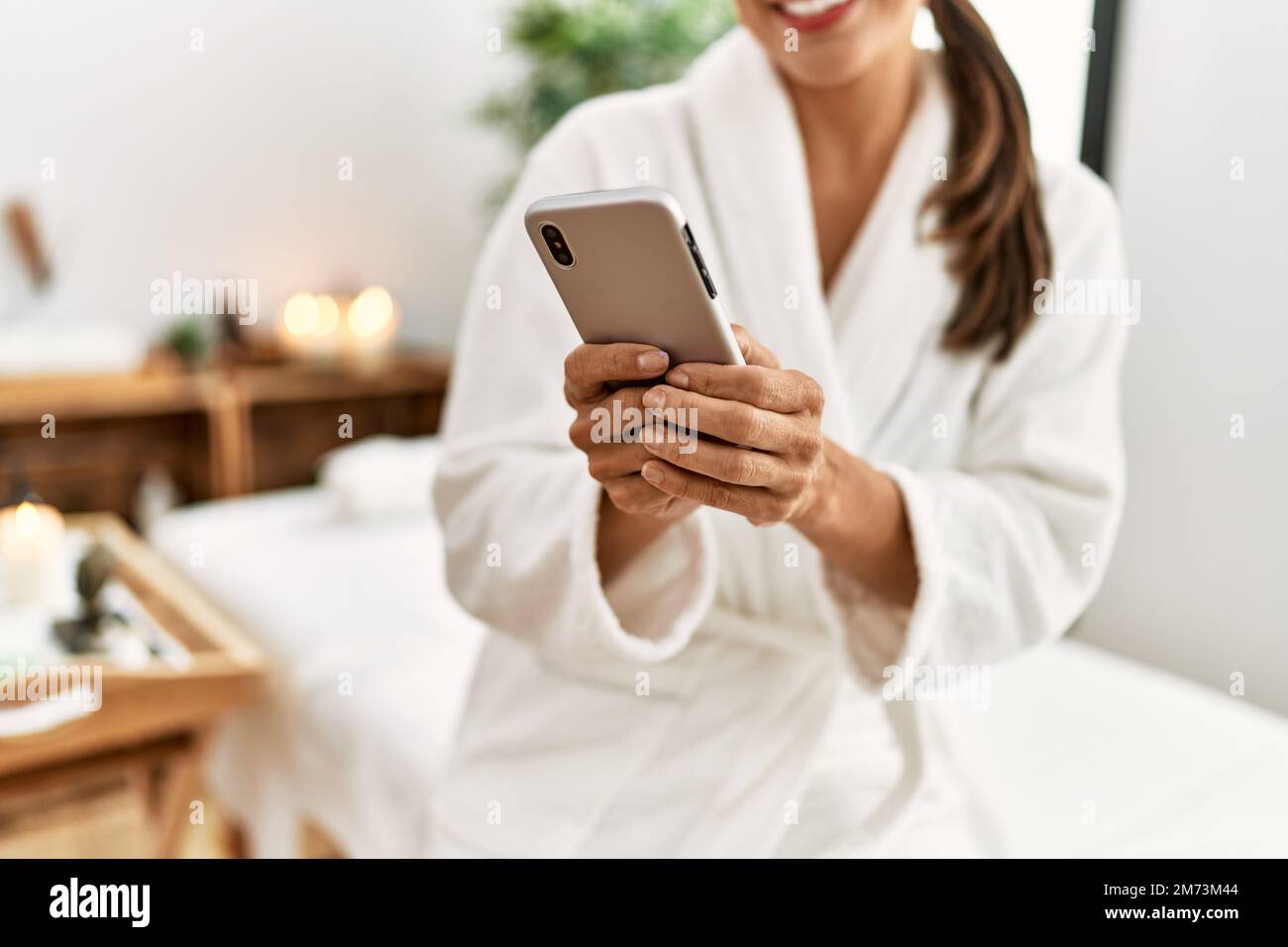 Young latin woman wearing bathrobe using smartphone Stock Photo - Alamy