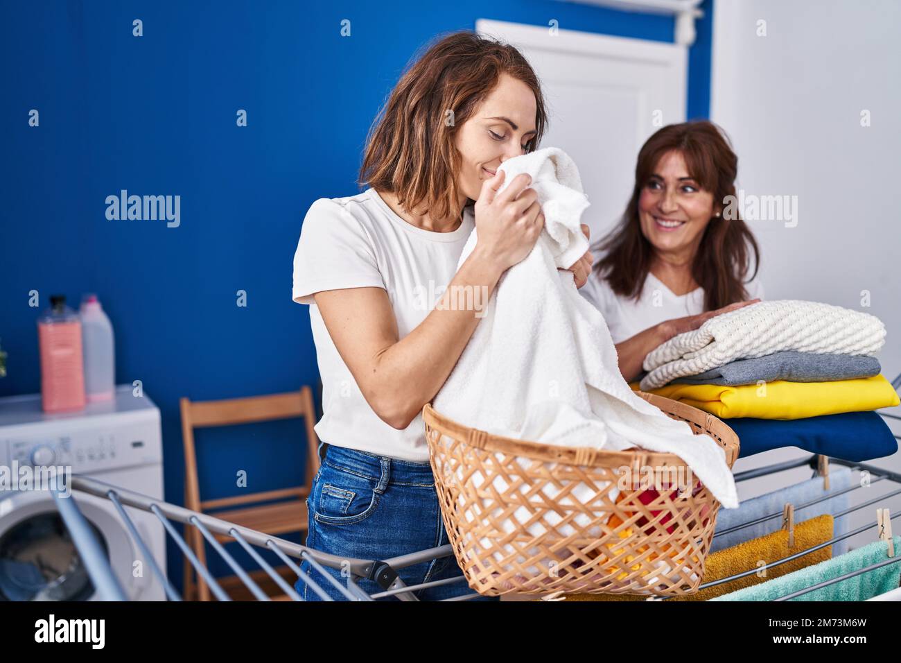 Two women mother and daughter smelling clean clothes at laundry room ...