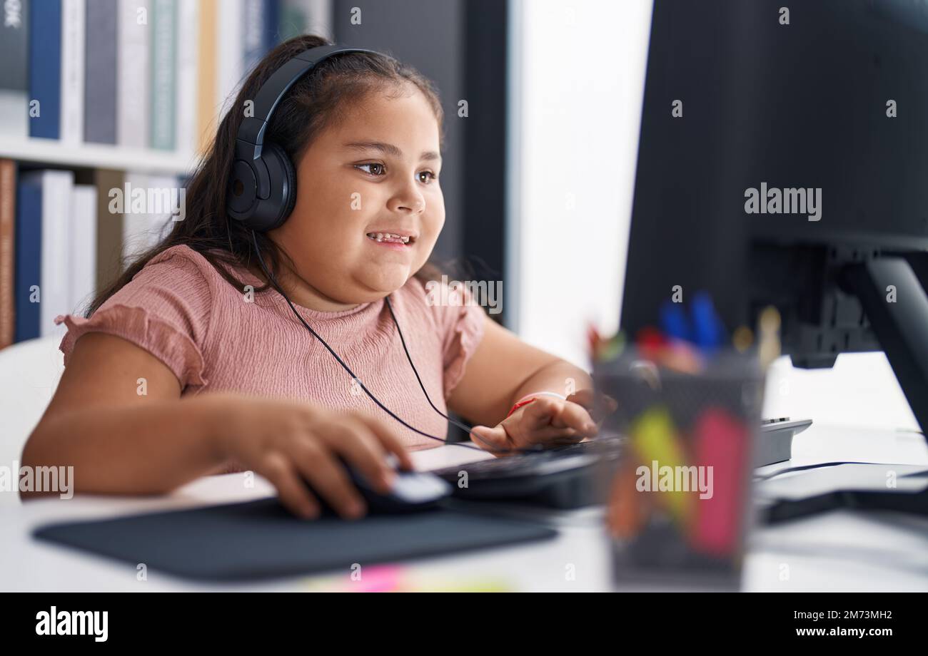 Plus size hispanic girl student using computer and headphones sitting ...