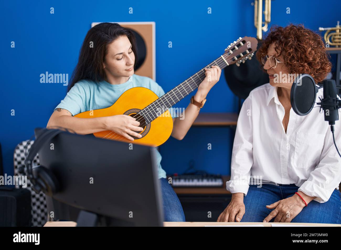 Two women musicians singing song playing classical guitar at music ...
