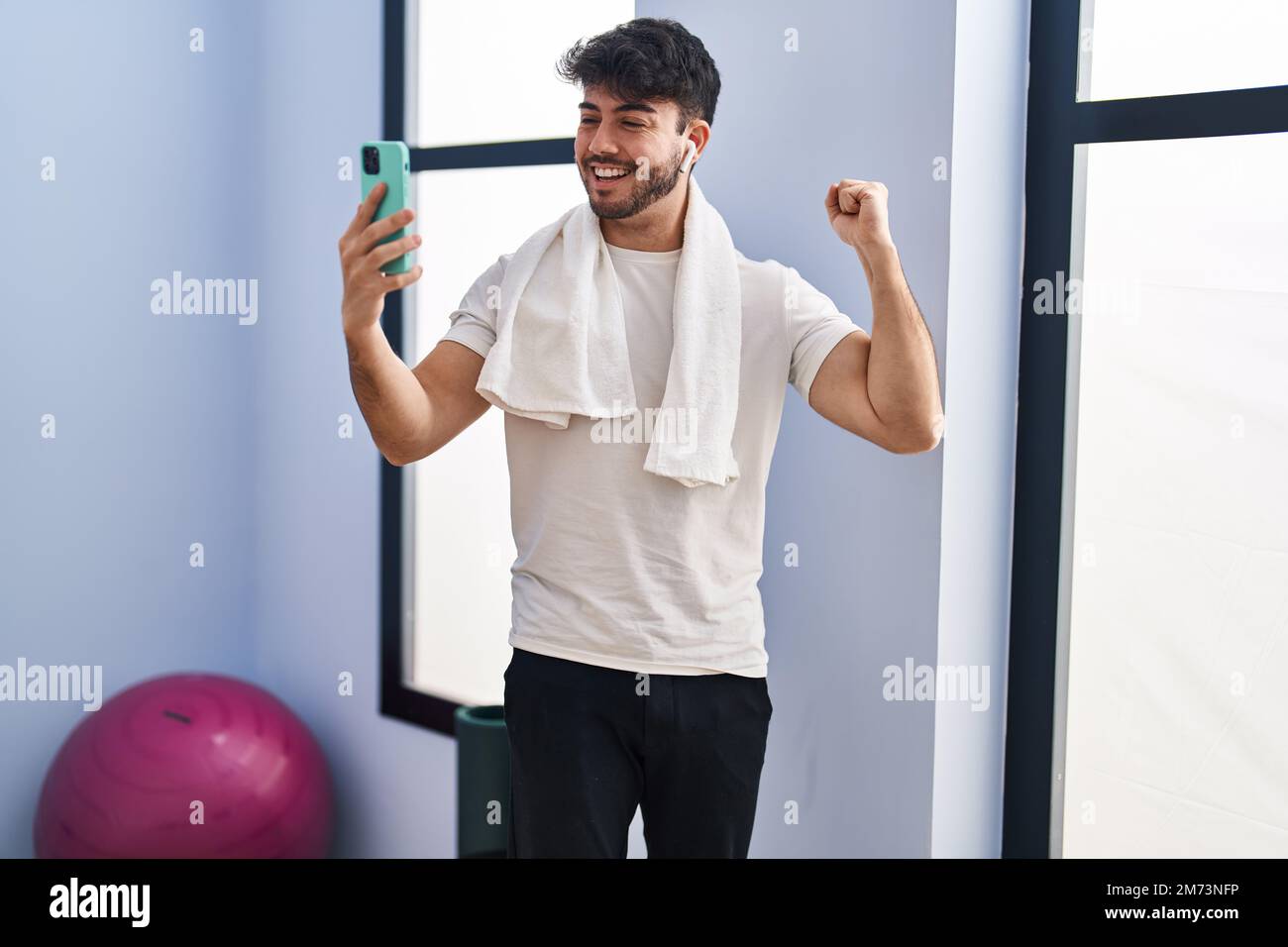Hispanic man with beard doing video call with smartphone at the gym ...