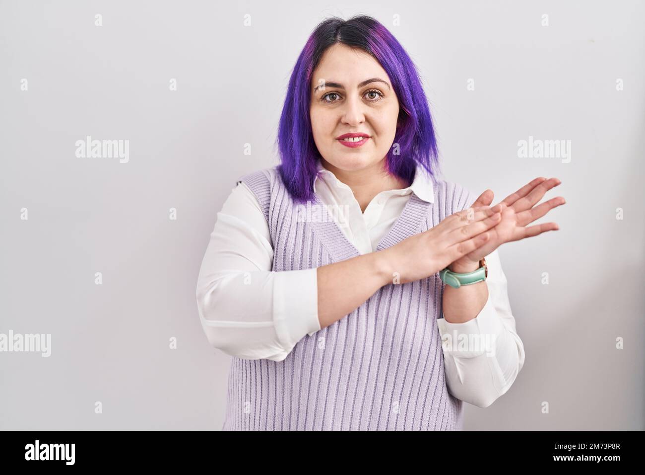 Plus size woman wit purple hair standing over white background clapping ...