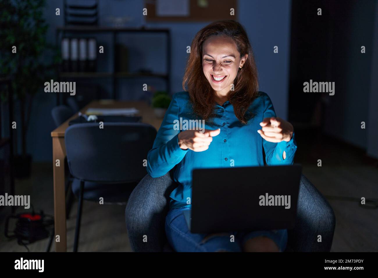 Brunette woman working at the office at night pointing fingers to ...