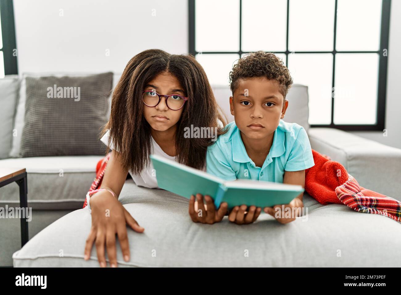 Two siblings lying on the sofa reading a book depressed and worry for ...