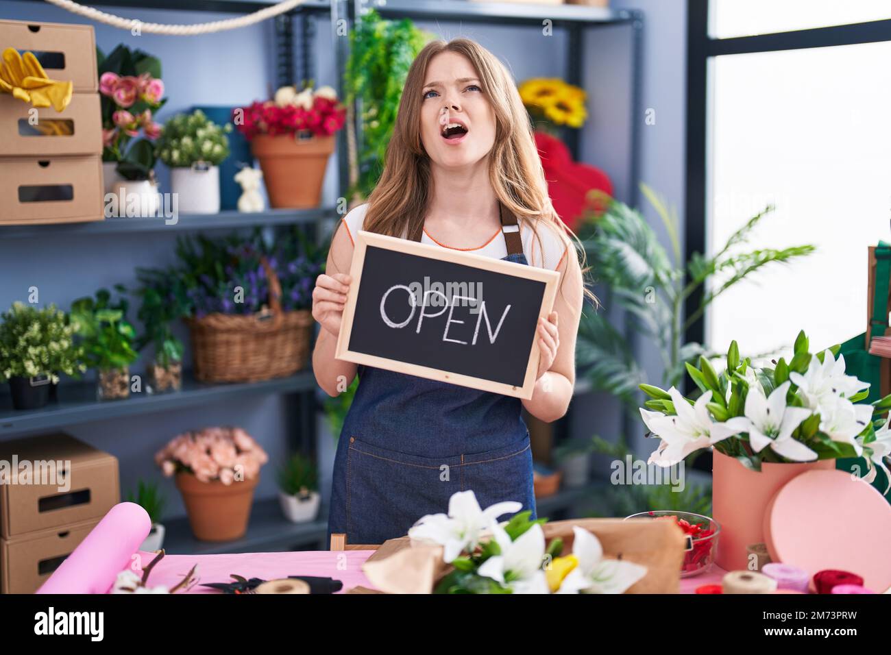 Caucasian woman working at florist holding open sign angry and mad ...