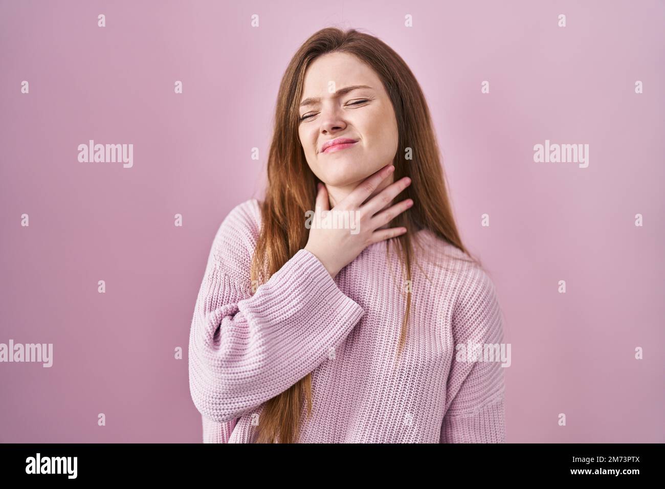 Young caucasian woman standing over pink background touching painful ...