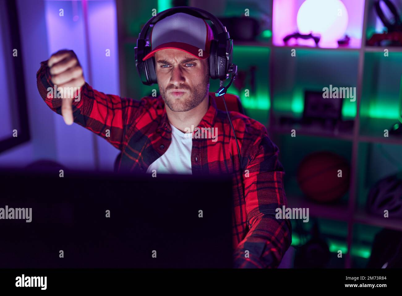 Young caucasian man playing video games with angry face, negative sign ...
