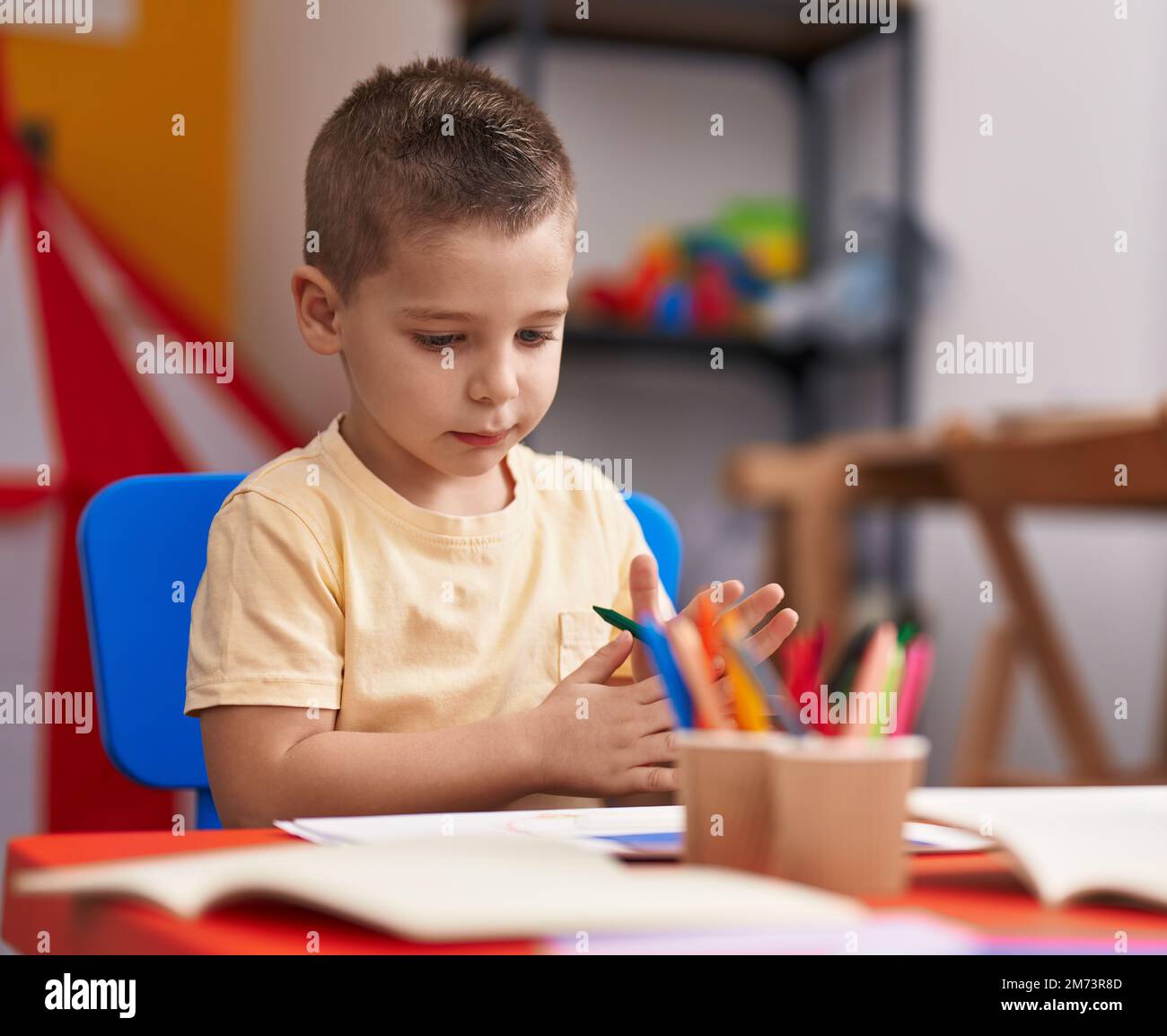 Adorable toddler student drawing on notebook sitting on table at ...