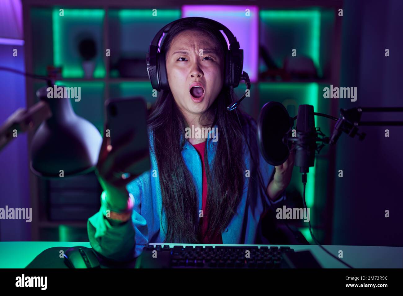 Young asian woman playing video games with smartphone angry and mad ...