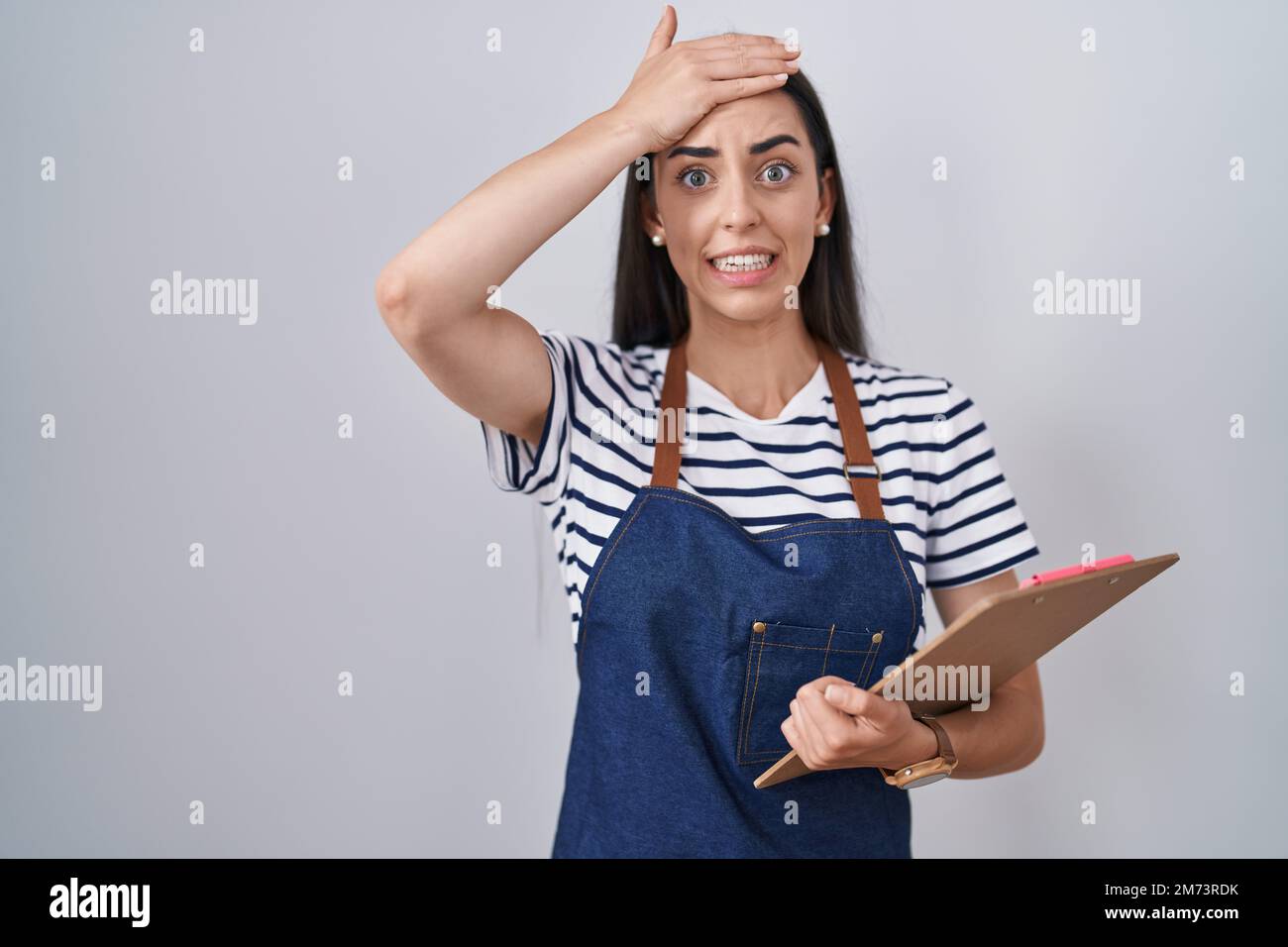 Young brunette woman wearing professional waitress apron and clipboard ...