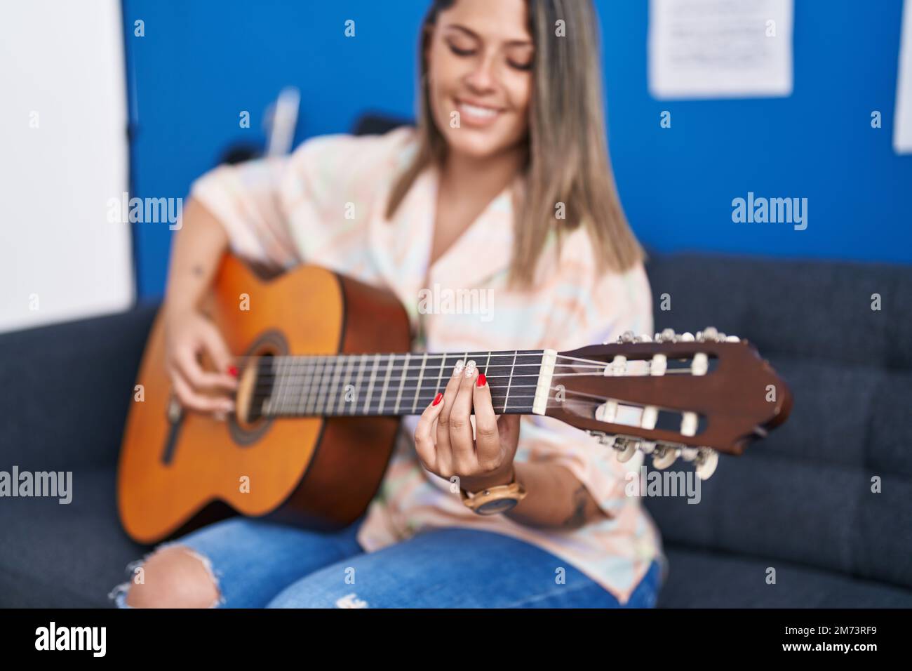 Young hispanic woman musician playing classical guitar at music studio ...