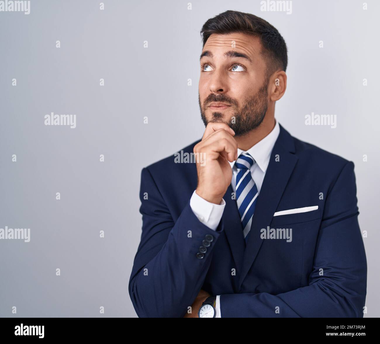 Handsome hispanic man wearing suit and tie with hand on chin thinking ...