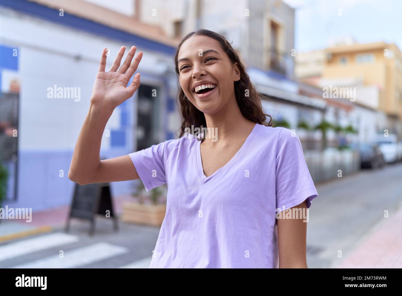 Young african american woman smiling confident saying hello with hand ...