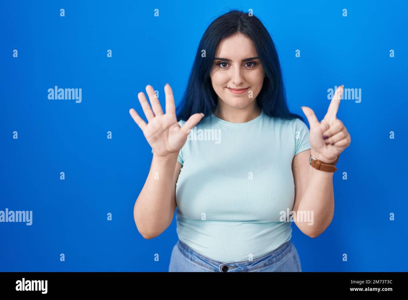 Young Modern Girl With Blue Hair Standing Over Blue Background Showing 1702