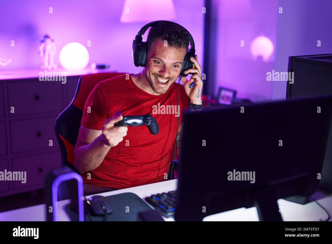 Young hispanic man streamer playing video game using joystick at gaming ...