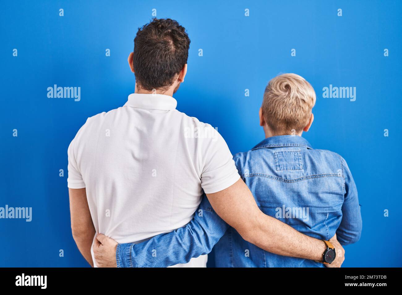 Young brazilian mother and son standing over blue background hugging ...