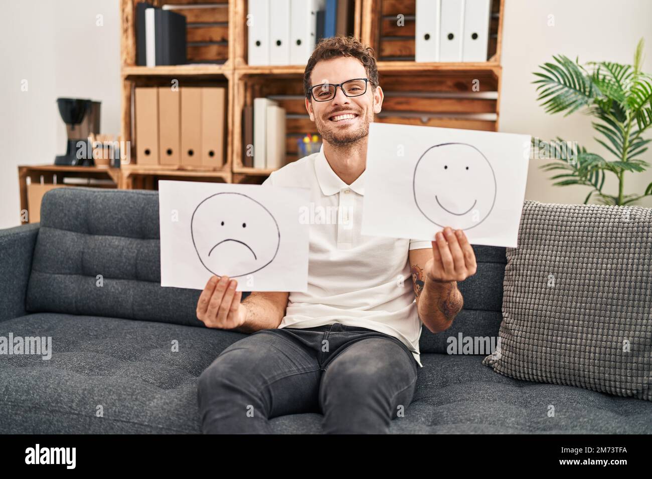 Young hispanic man working on depression holding sad to happy emotion ...