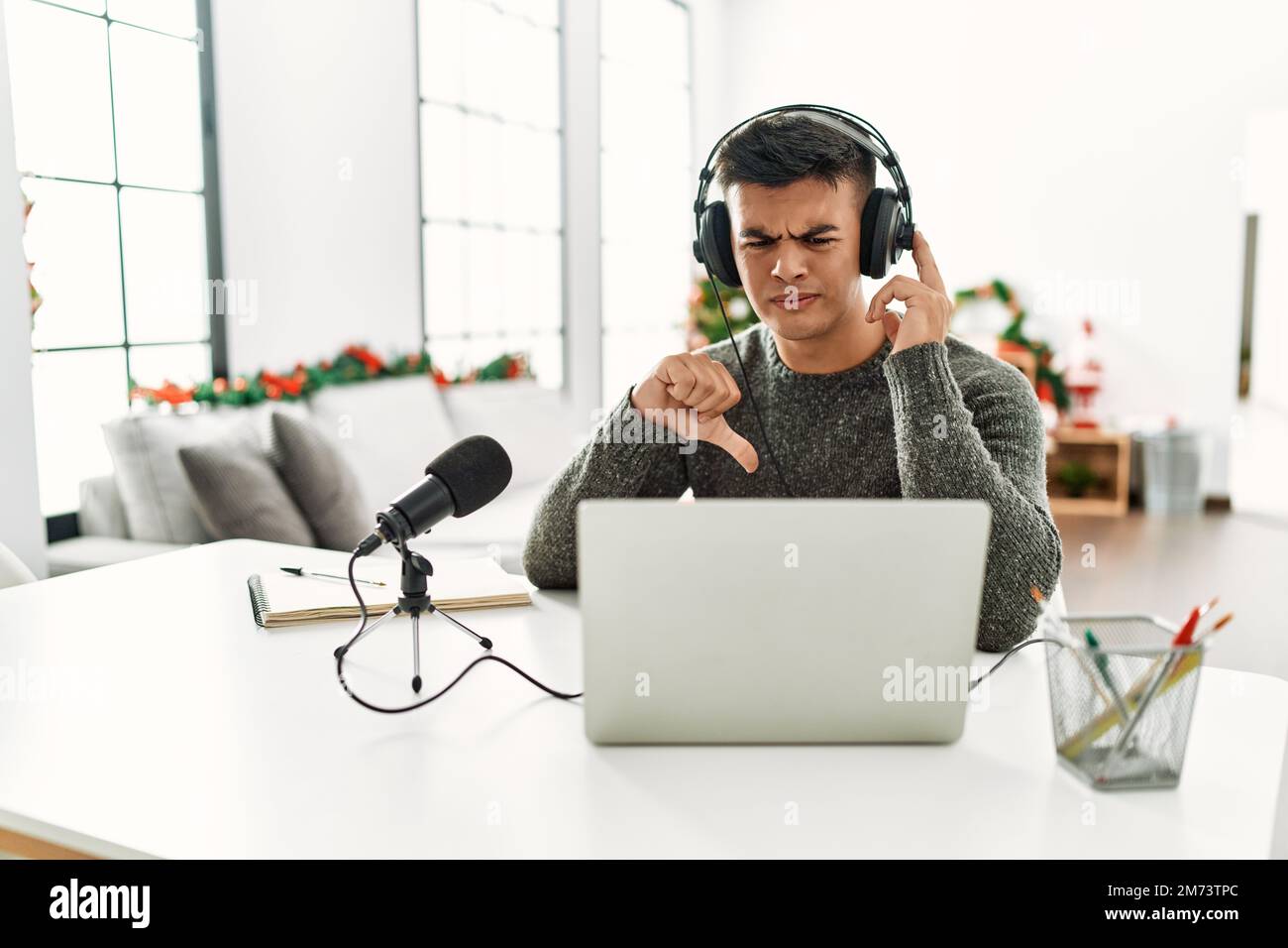 Handsome hispanic man recording podcast with angry face, negative sign ...