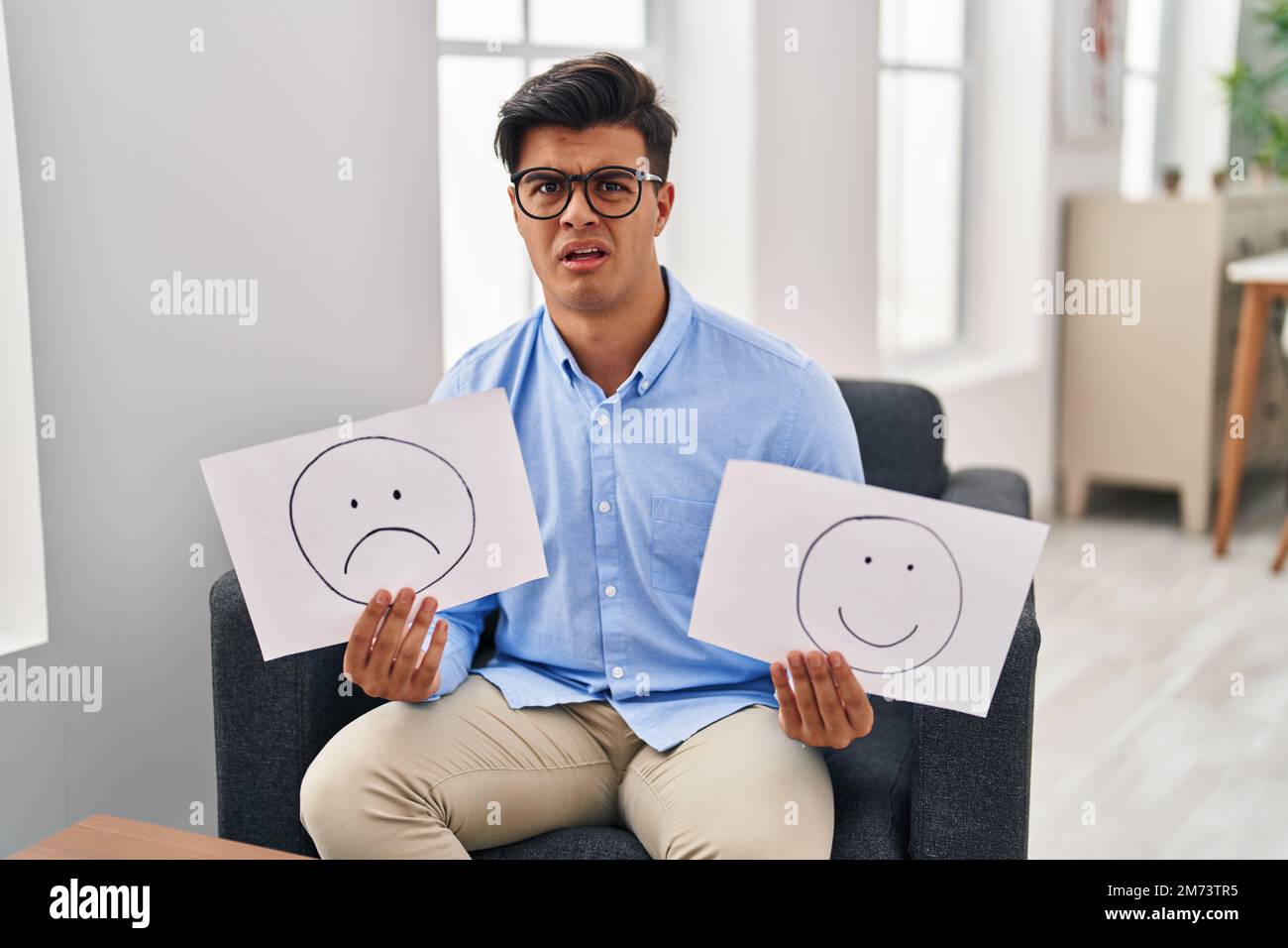 Hispanic man working on depression holding sad to happy emotion paper ...