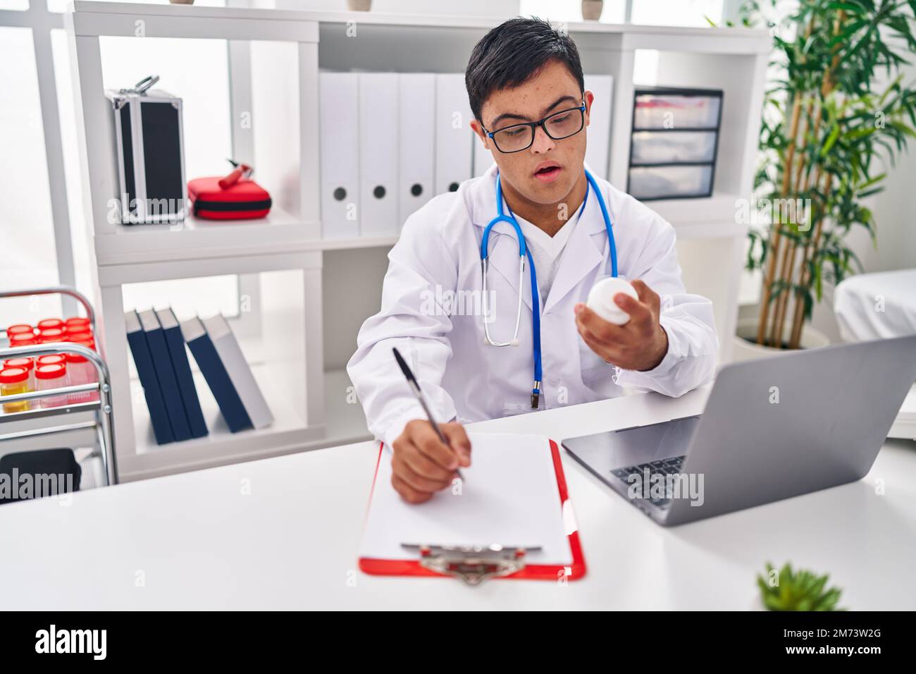 Down syndrome man wearing doctor uniform prescribe pills at clinic ...