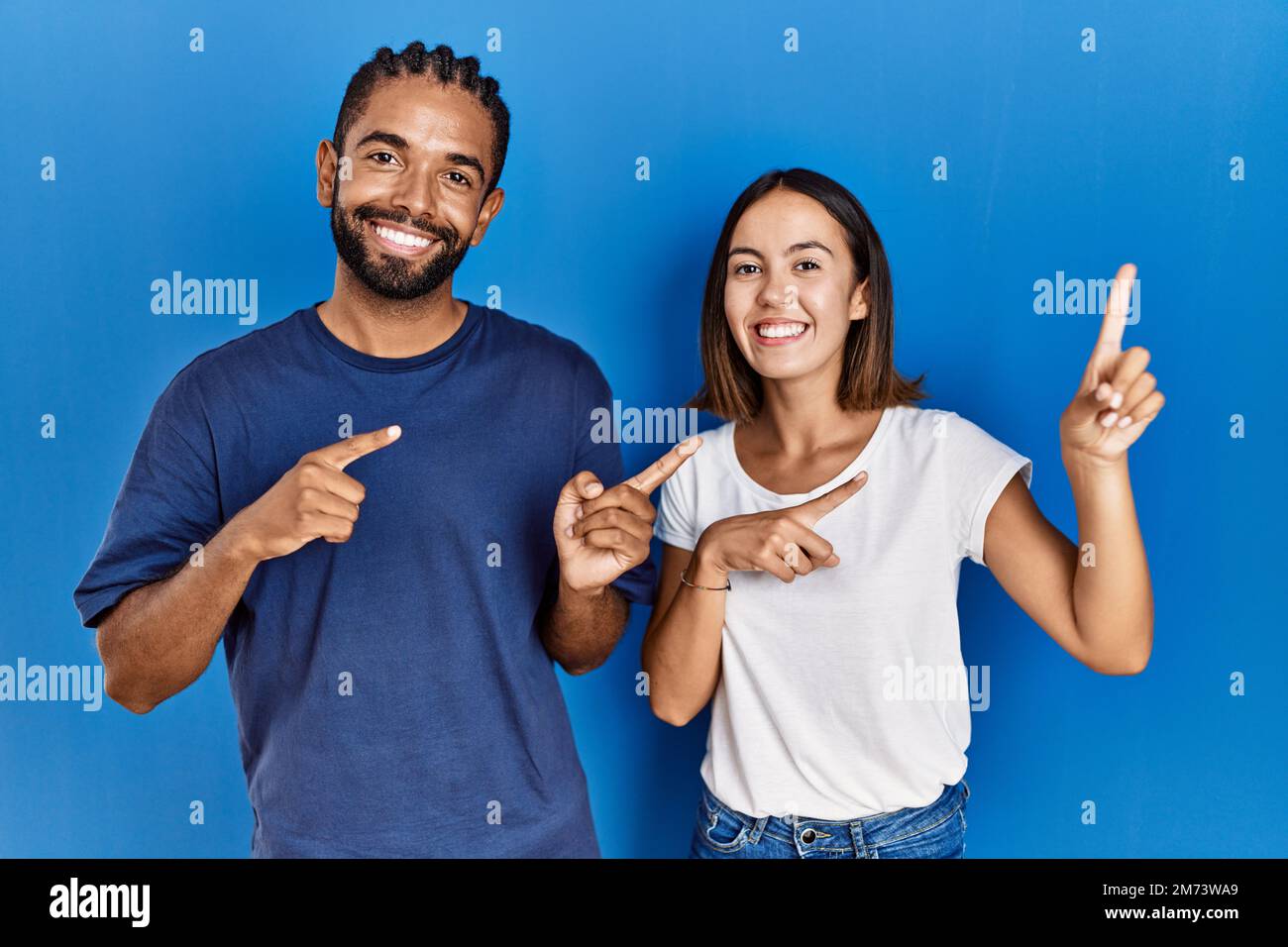 Young hispanic couple standing together smiling and looking at the ...