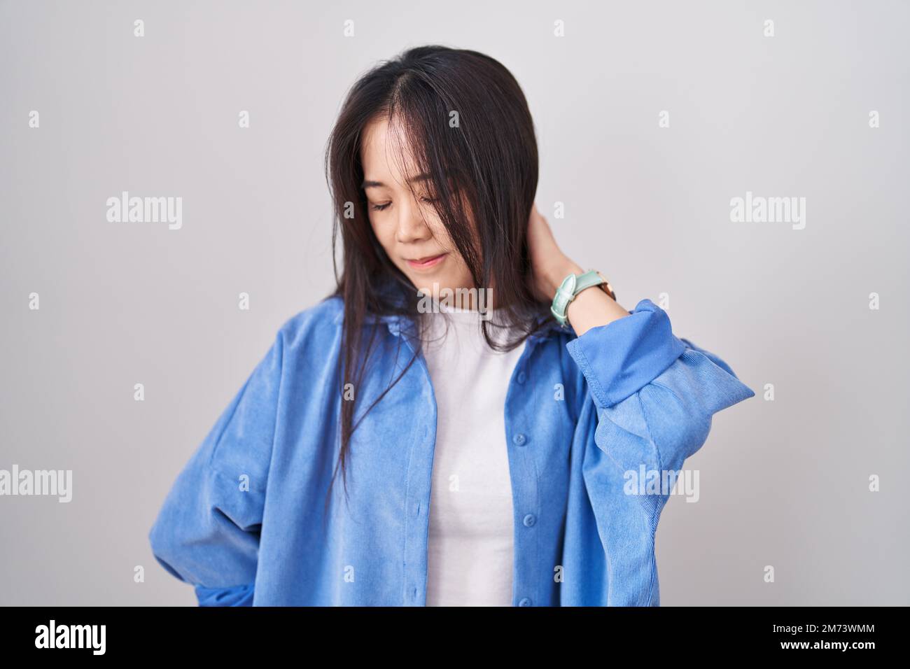 Young chinese woman standing over white background suffering of neck ...