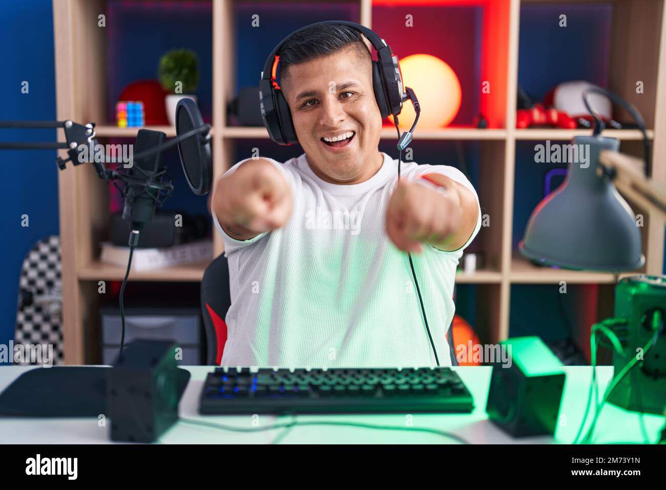 Young hispanic man playing video games pointing to you and the camera ...