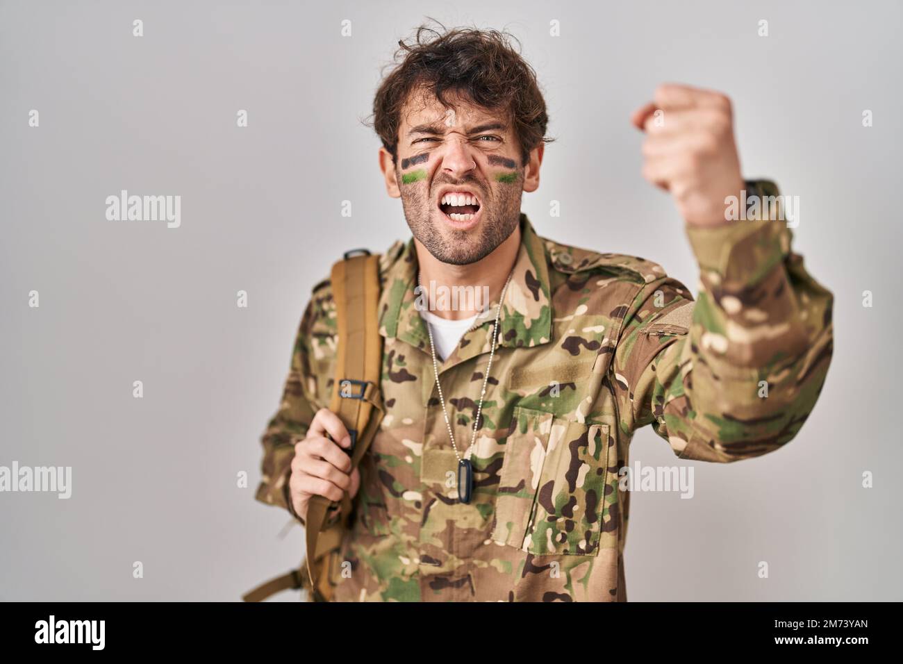 Hispanic young man wearing camouflage army uniform angry and mad ...