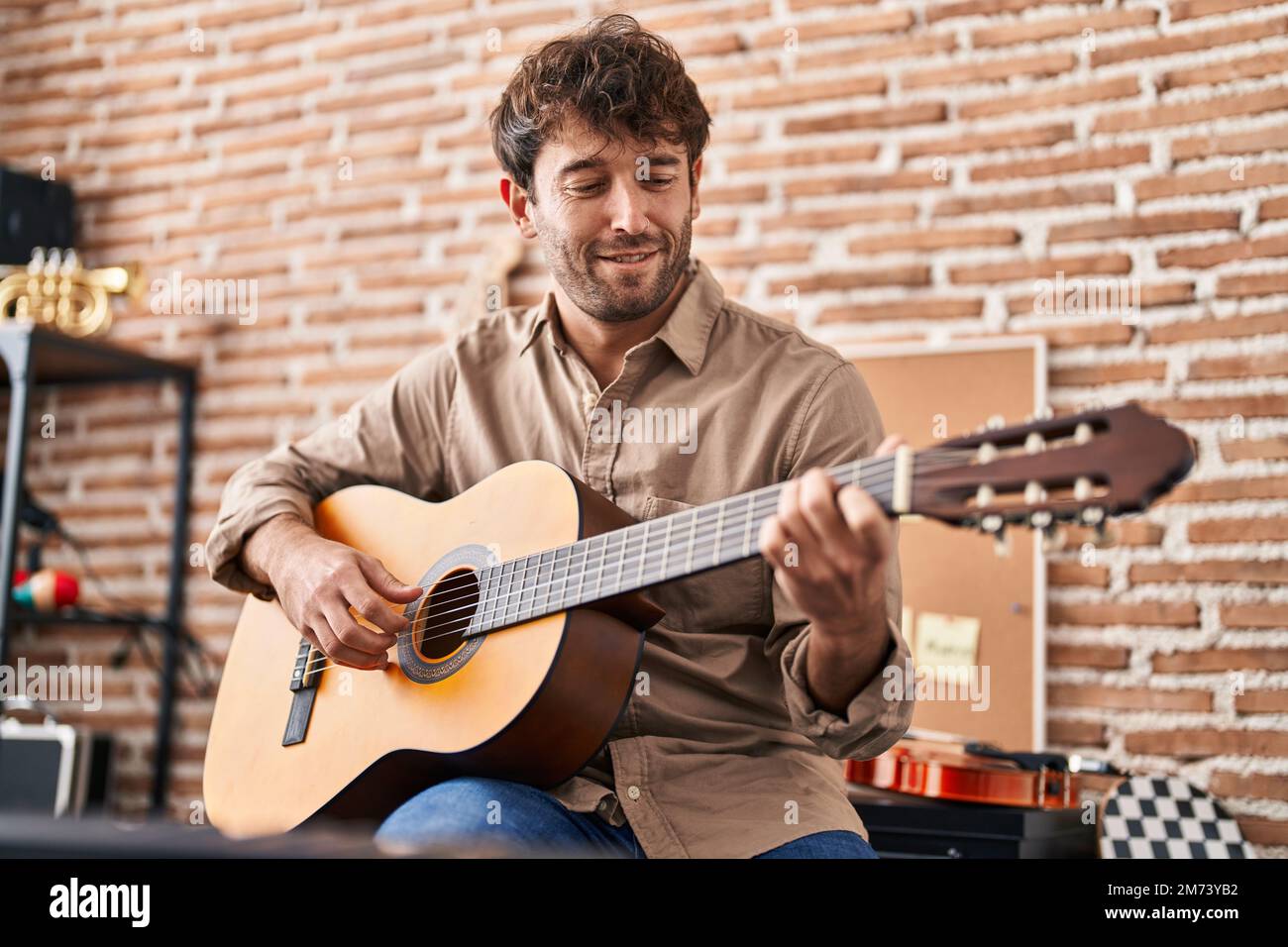 Young man musician smiling confident playing classical guitar at music ...