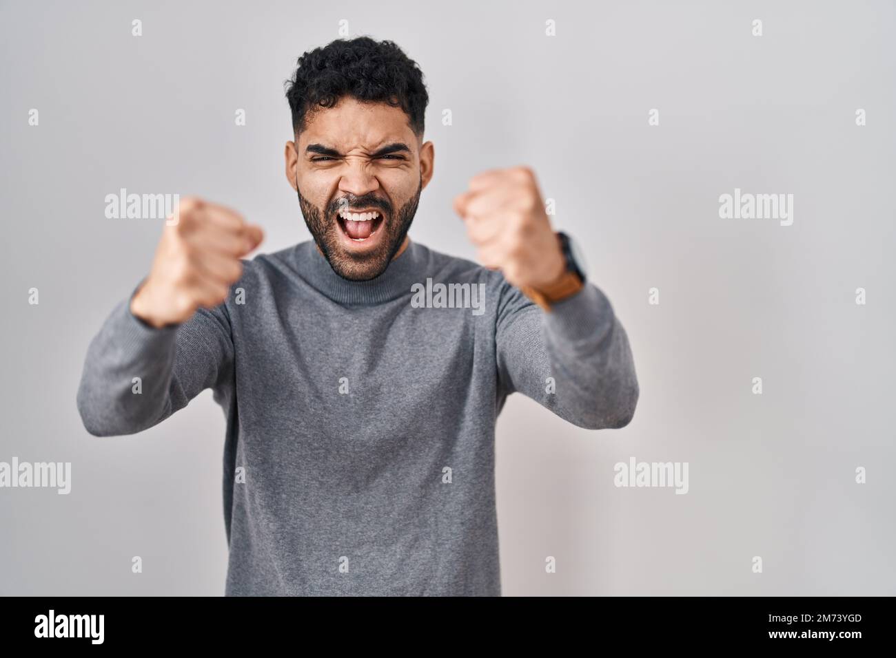Hispanic man with beard standing over white background angry and mad ...