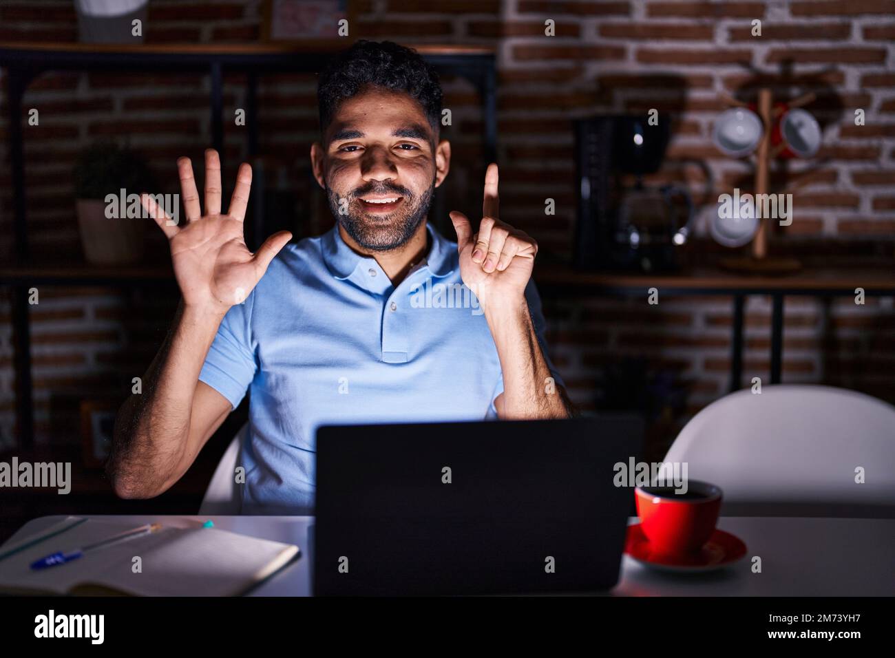 Hispanic man with beard using laptop at night showing and pointing up ...