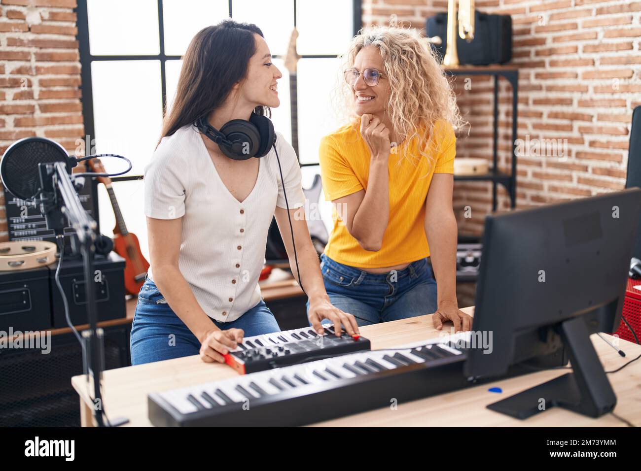 Two women musicians composing song using keyboard at music studio Stock ...