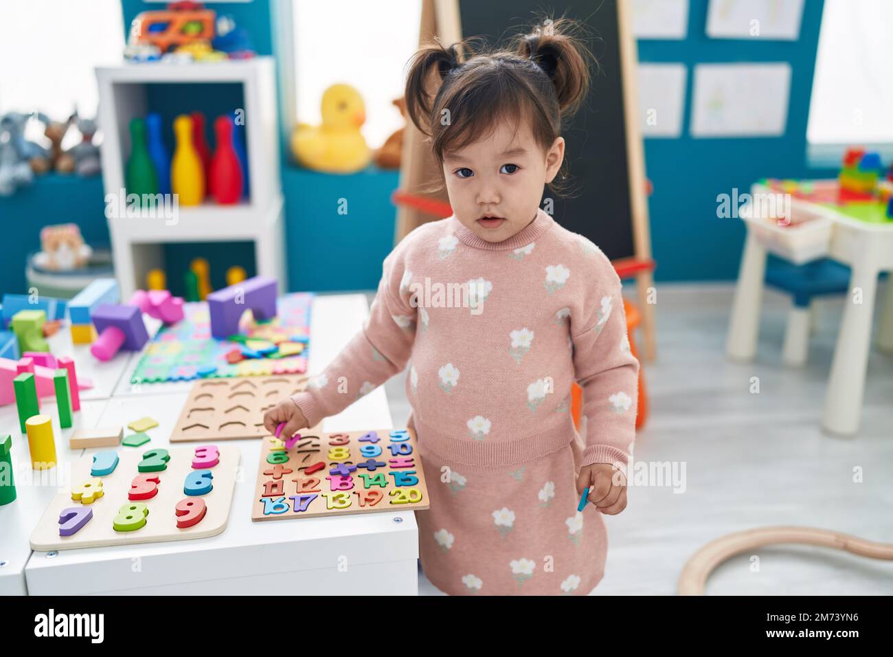 Adorable chinese girl playing with maths puzzle game standing at ...