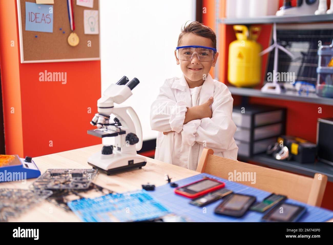 Adorable hispanic toddler student using microscope standing with arms ...