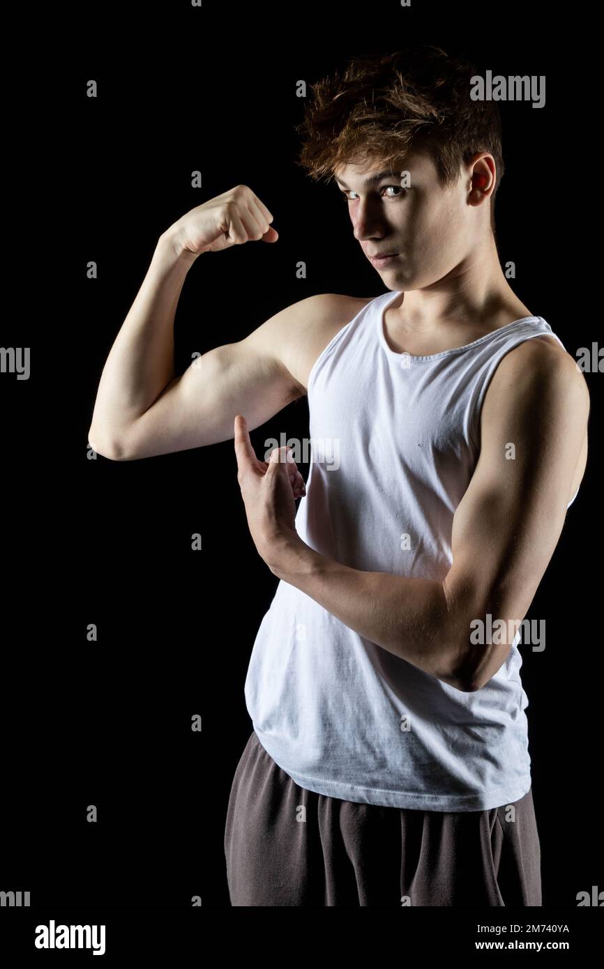 A 17 year old teenage boy wearing a white tank top flexing his arm ...