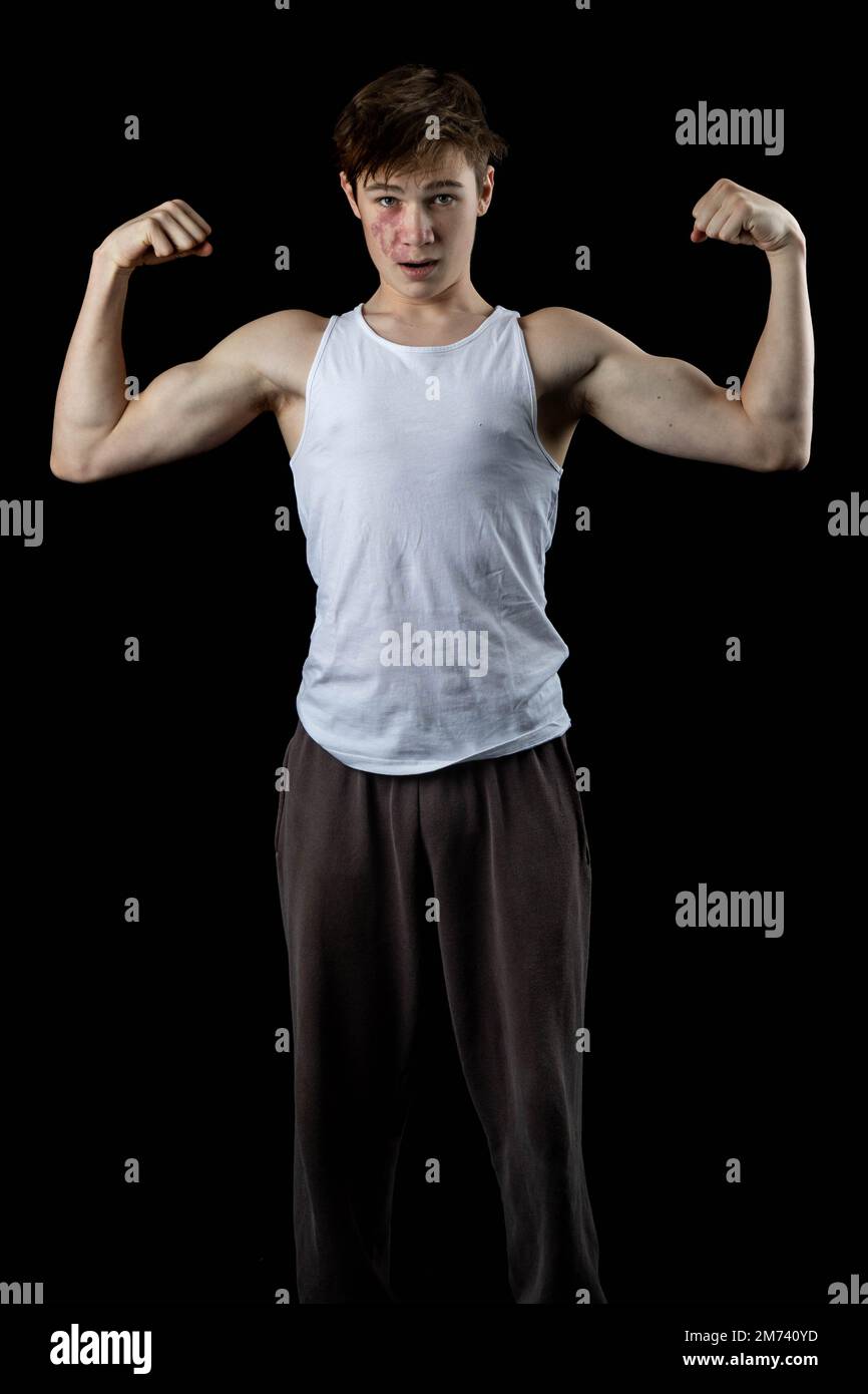 A 17 year old teenage boy wearing a white tank top flexing his arm ...