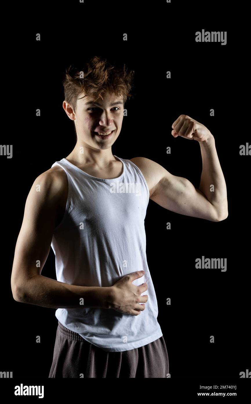 A 17 year old teenage boy wearing a white tank top flexing his arm ...