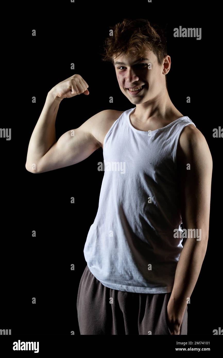 A 17 year old teenage boy wearing a white tank top flexing his arm ...