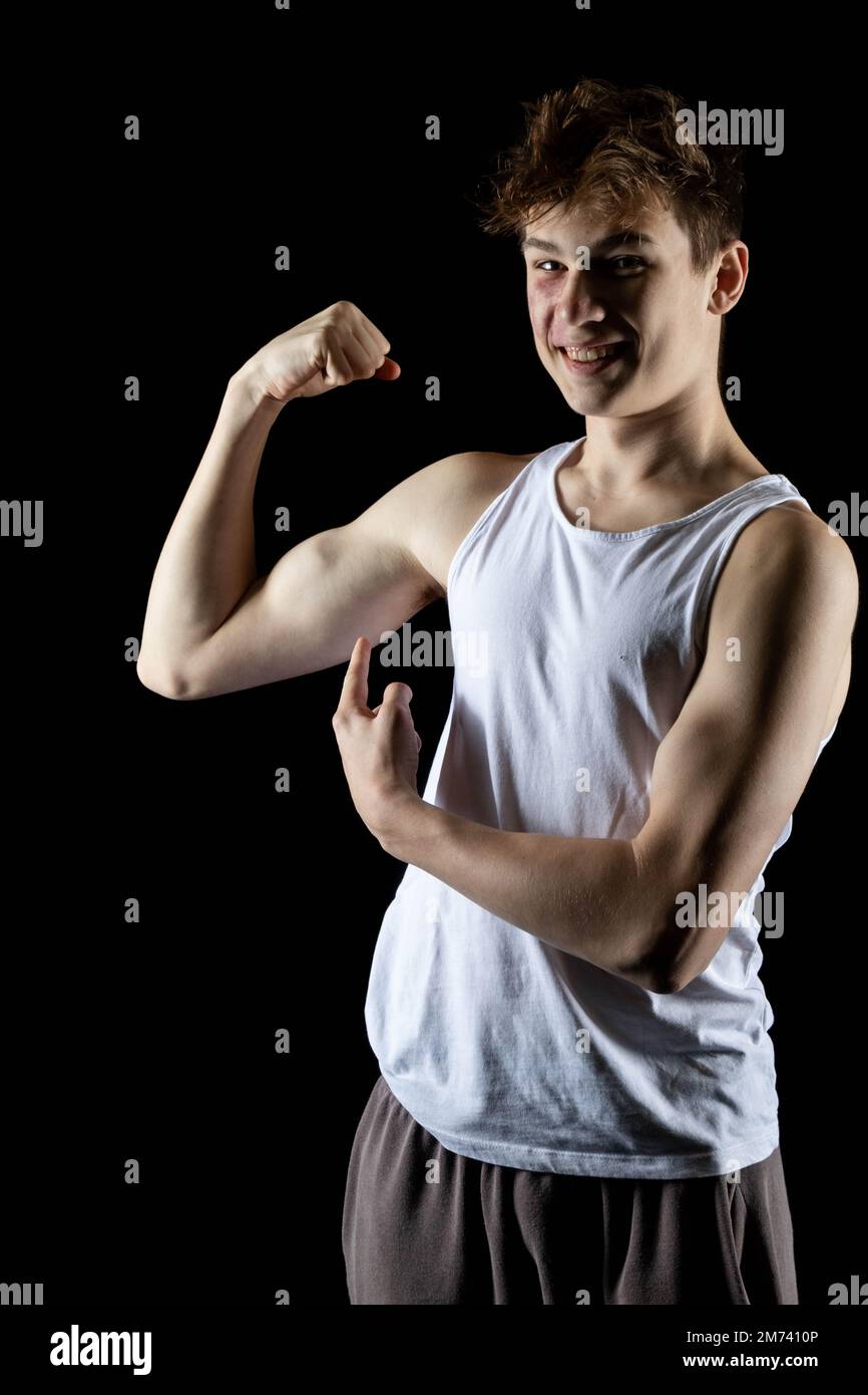 A 17 year old teenage boy wearing a white tank top flexing his arm ...