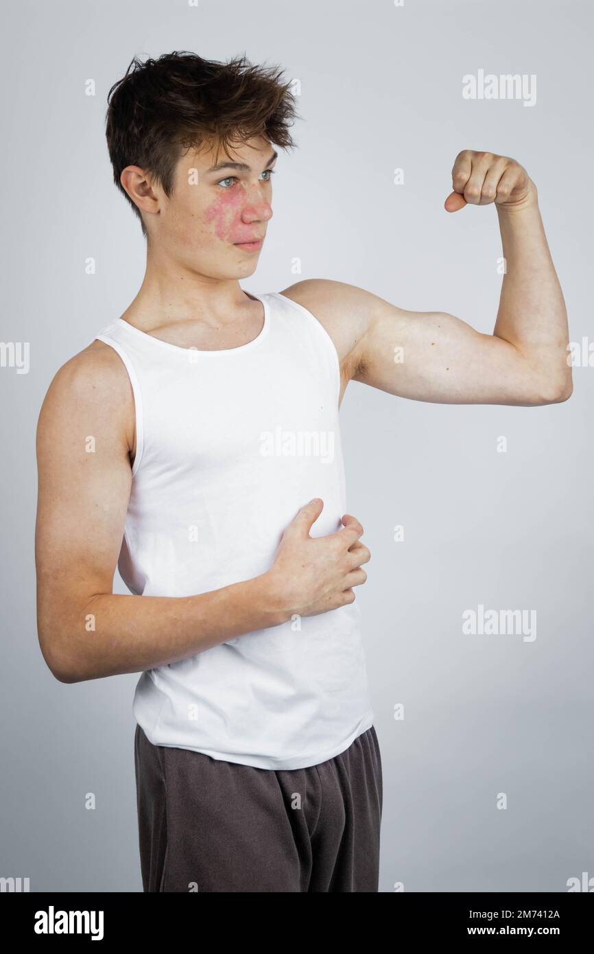 A 17 year old teenage boy wearing a white tank top flexing his arm ...