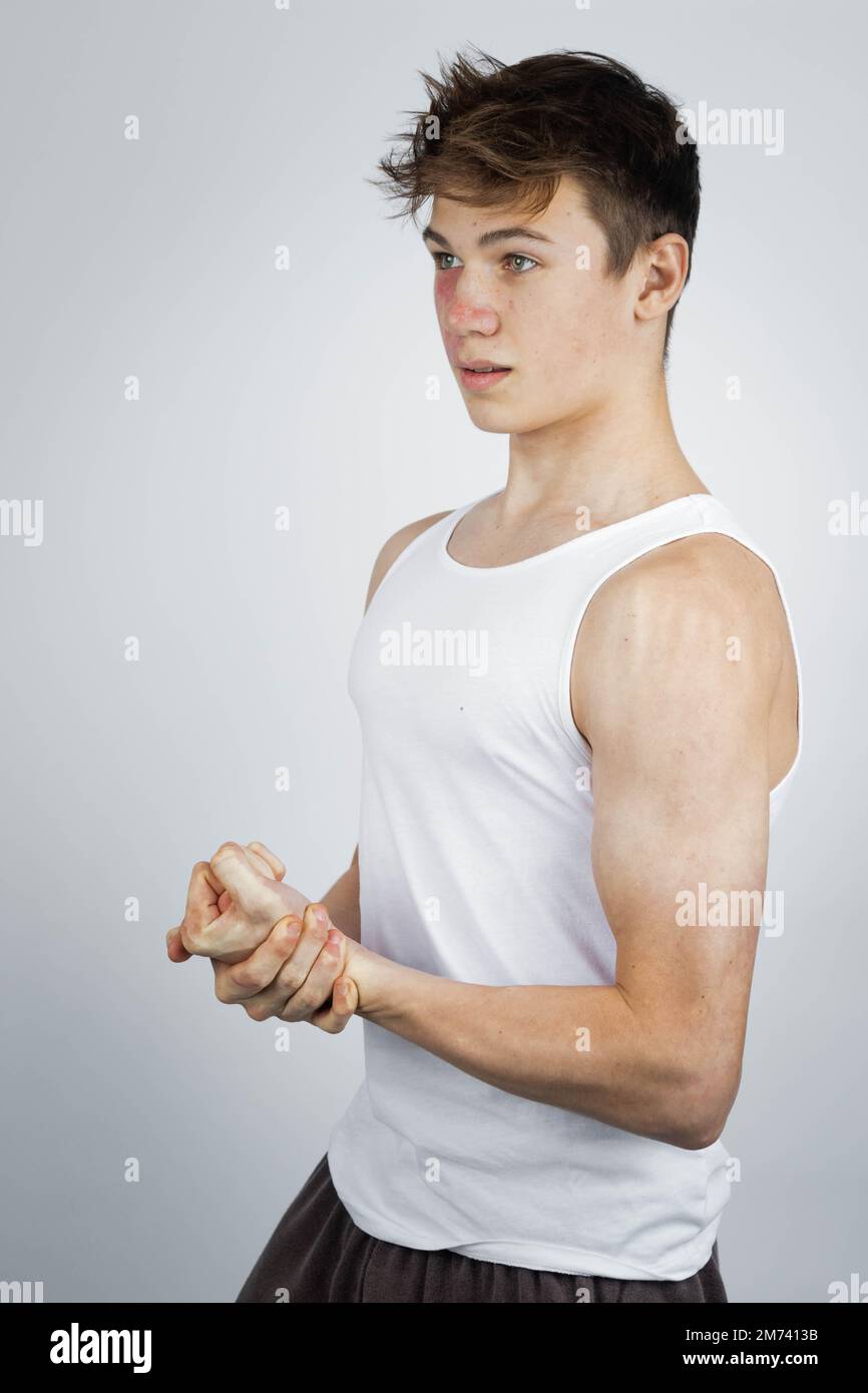 A 17 year old teenage boy wearing a white tank top flexing his arm ...